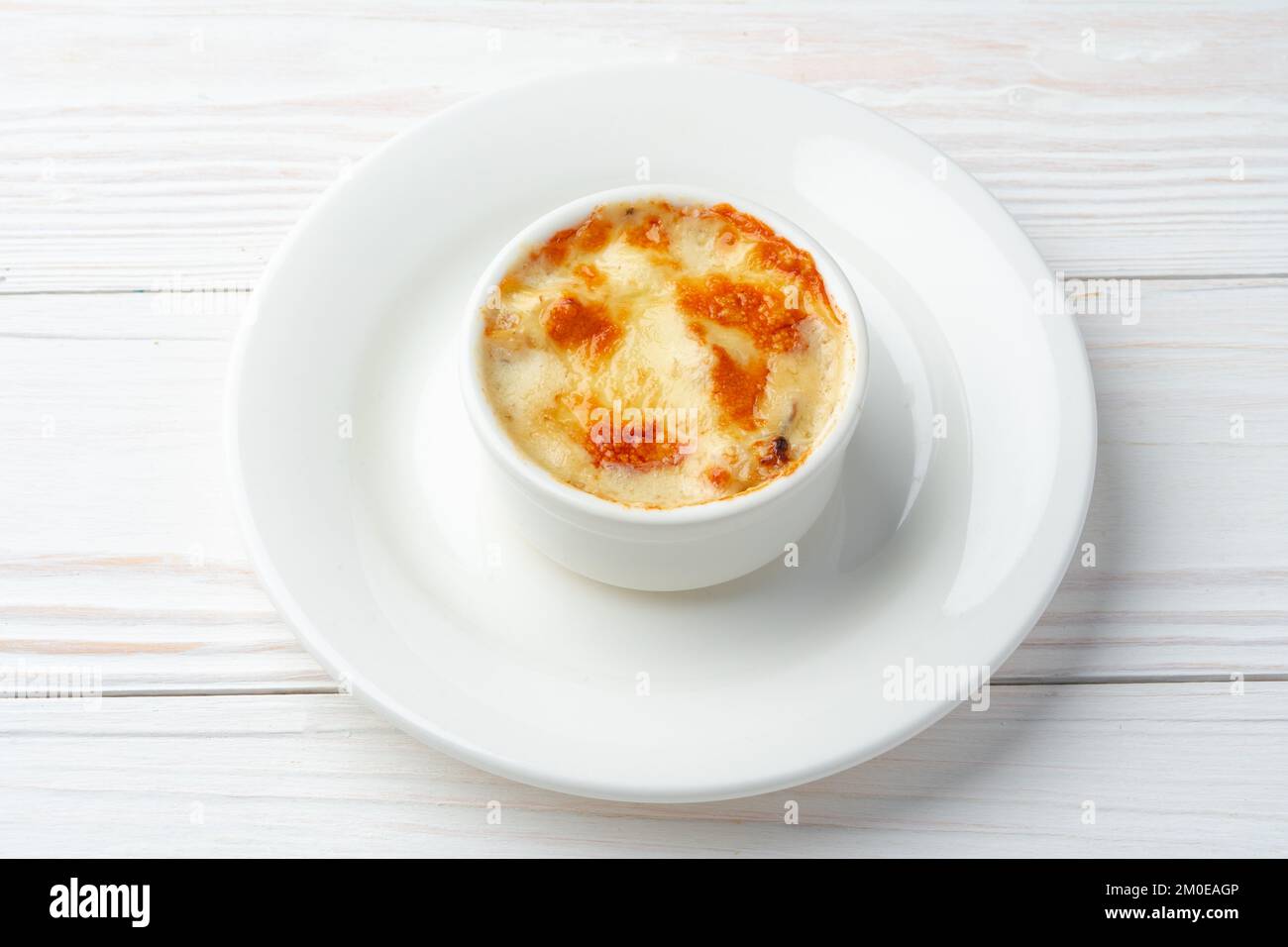 Baked julienne with mushrooms and cheese on top on white plate Stock ...