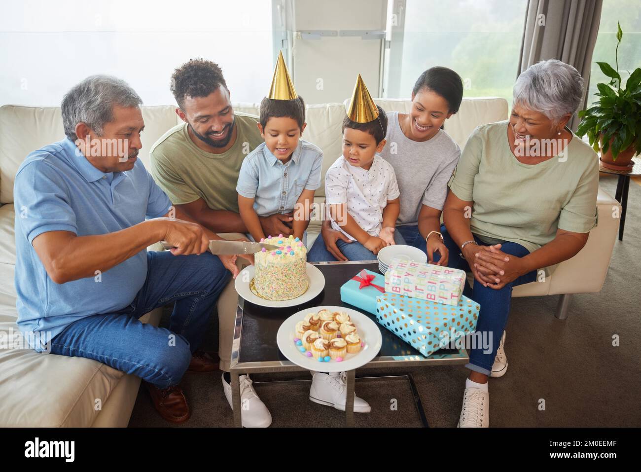 Mixed race family celebrating a birthday and having come cake at home ...