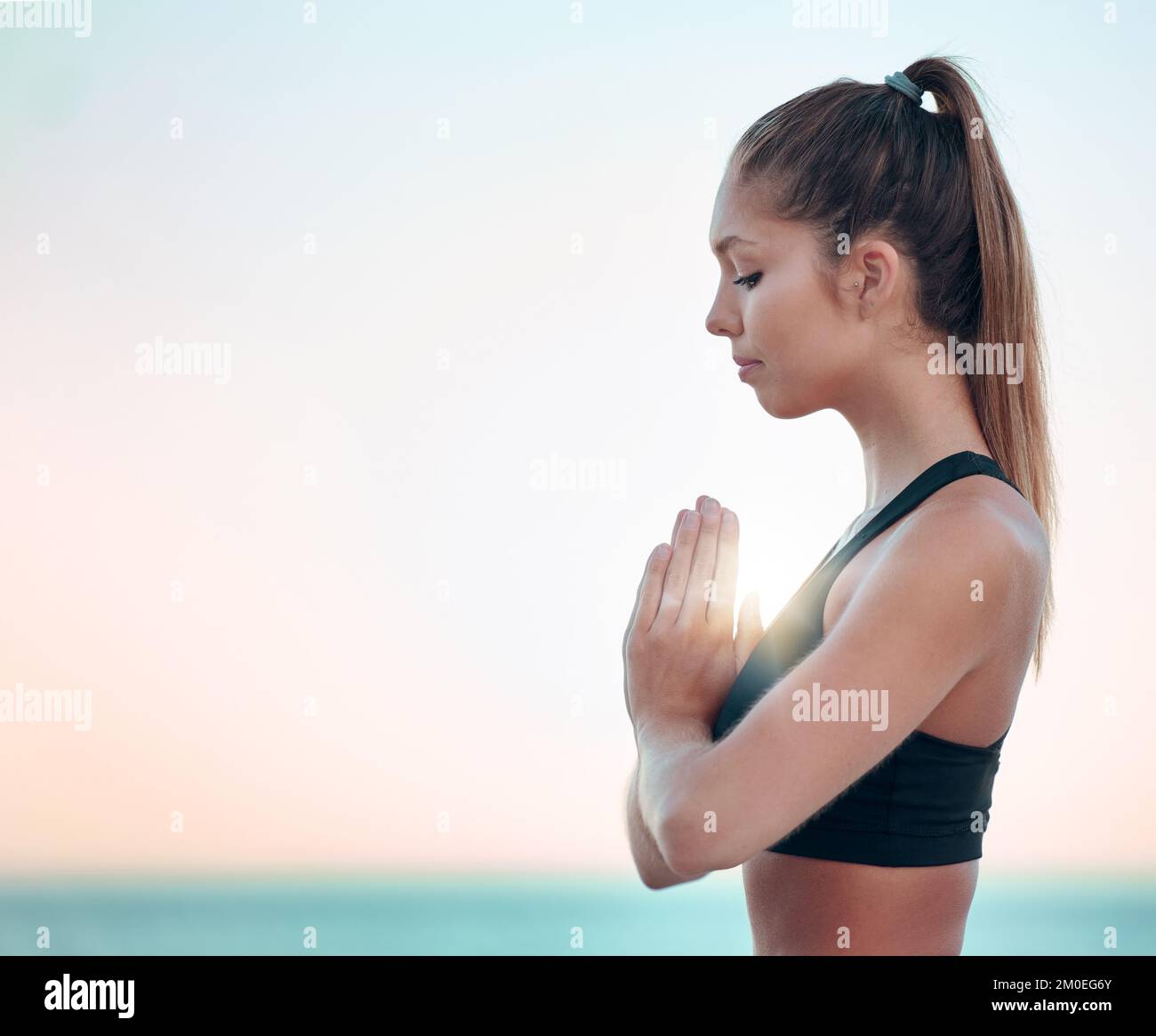 Beautiful woman meditating while practising yoga exercise on the beach ...
