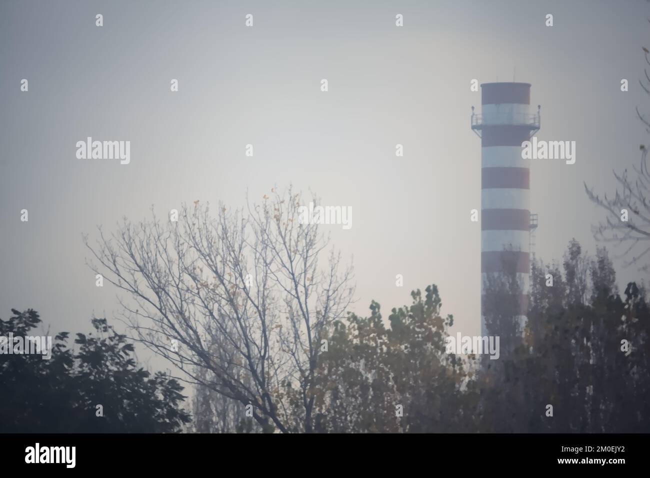 Red and white chimney framed by trees on a misty day in autumn Stock ...
