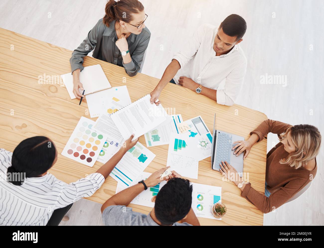 Group of diverse businesspeople from above passing paperwork to each ...