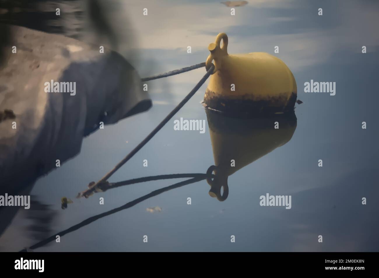 Buoy tied on a rope floating on water and casting its reflection Stock ...