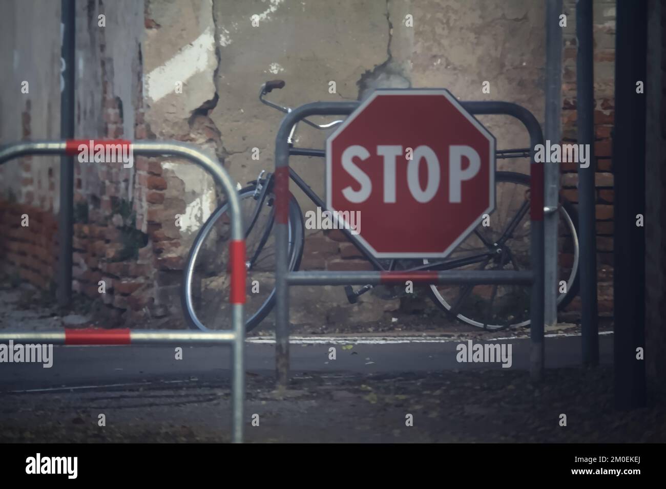 Bike leaning on a wall behind a bar and a stop sign on a misty day ...