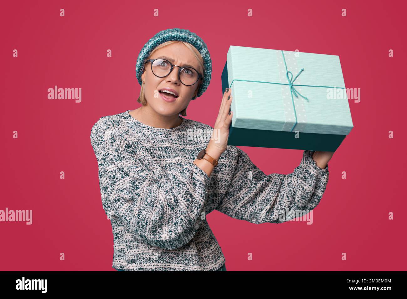Joyful woman holding present, shaking whapped box, guessing what's ...