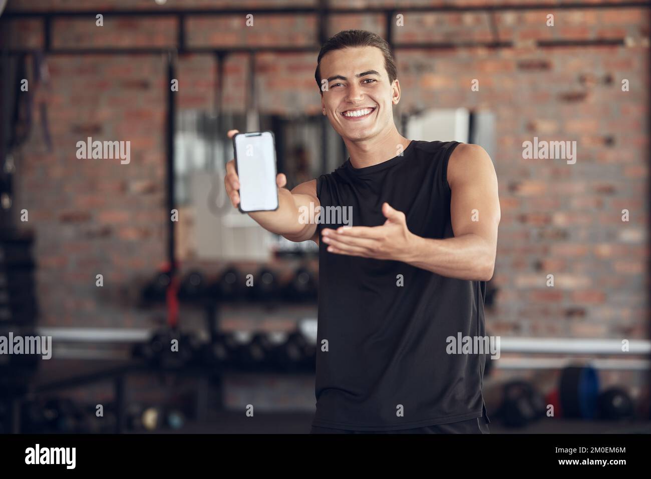 Young man showing the screen of his mobile device in the gym. Young man ...