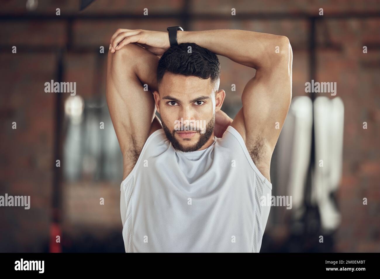 Portrait of young athlete stretching his arms in the gym. Young man ...