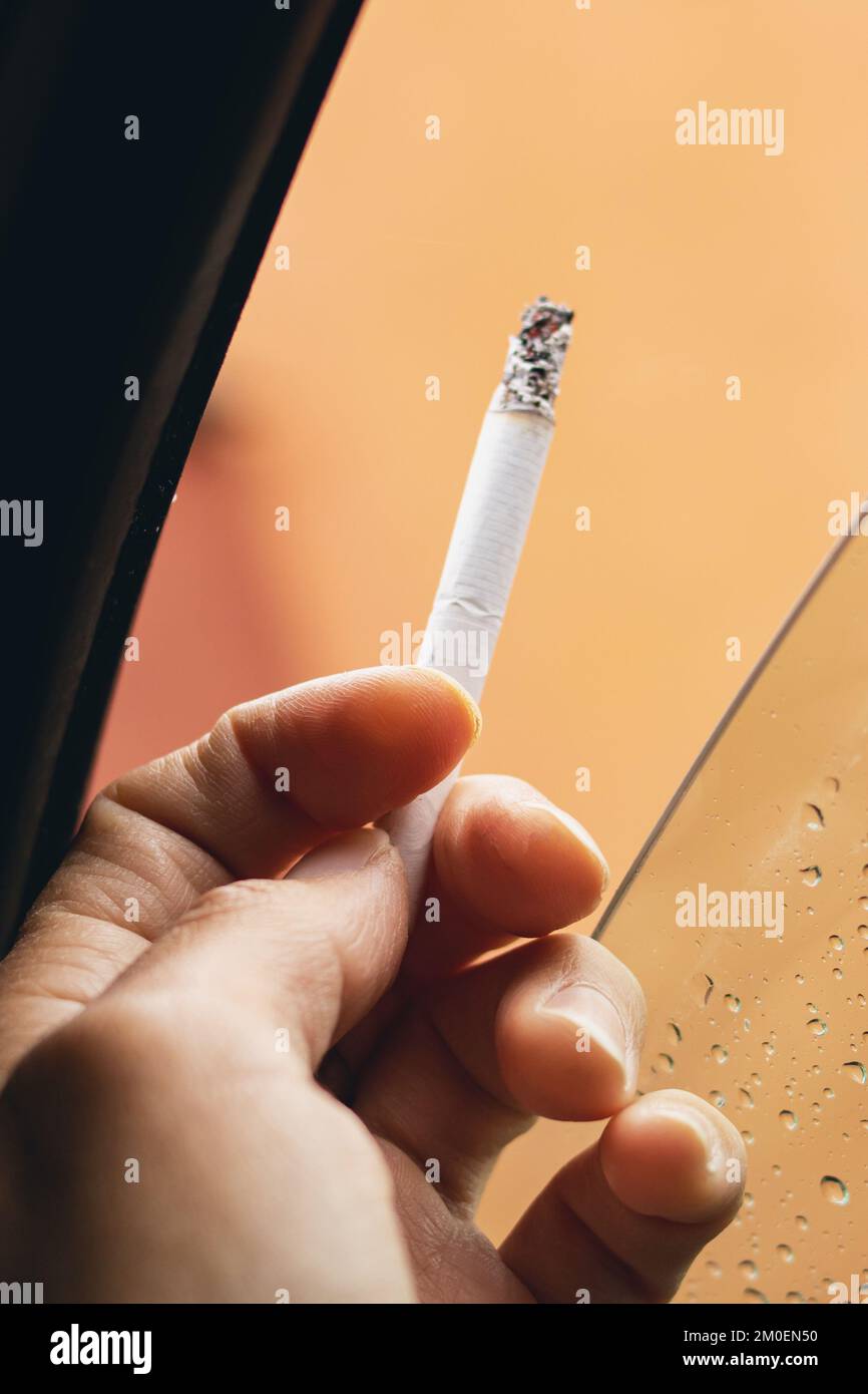 Cigarette in hand by the car window close up Stock Photo - Alamy