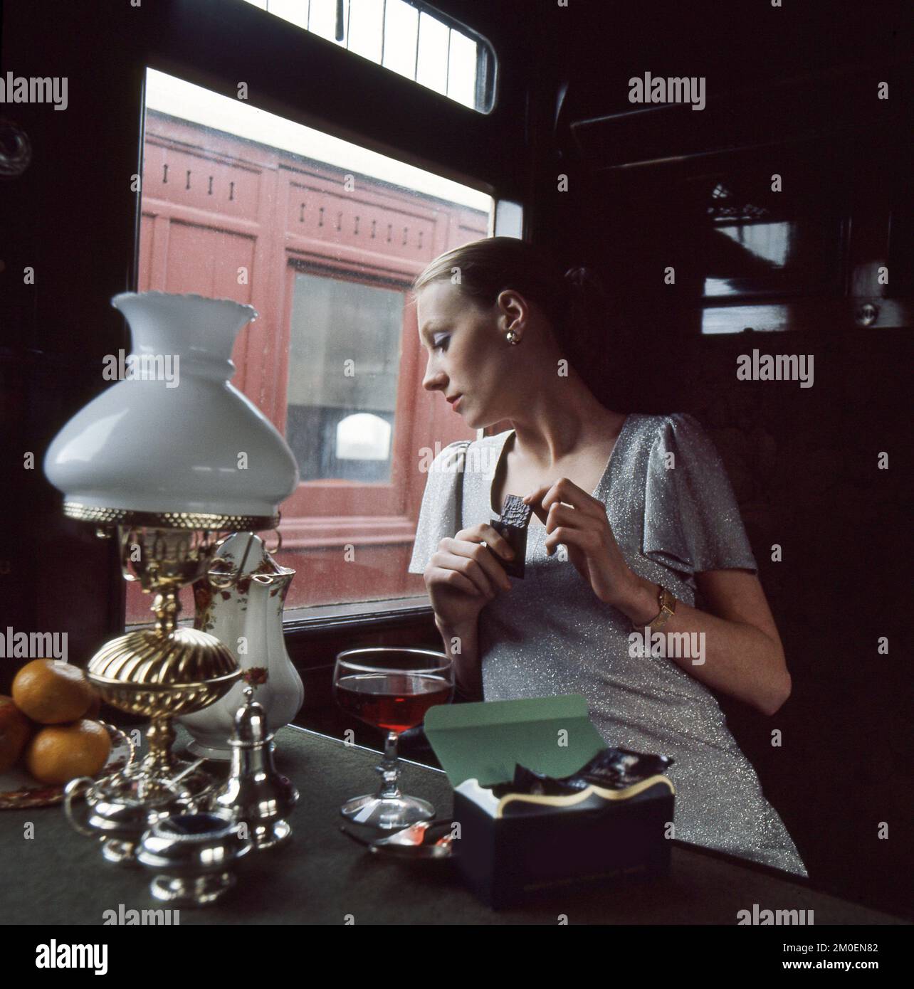 Young woman on a heritage railway train dining car in 1972 fashion ...