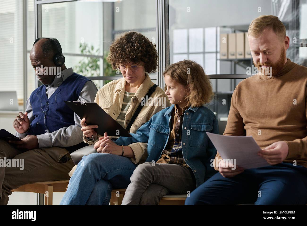 Portrait of mother and daughter waiting in line at state services ...