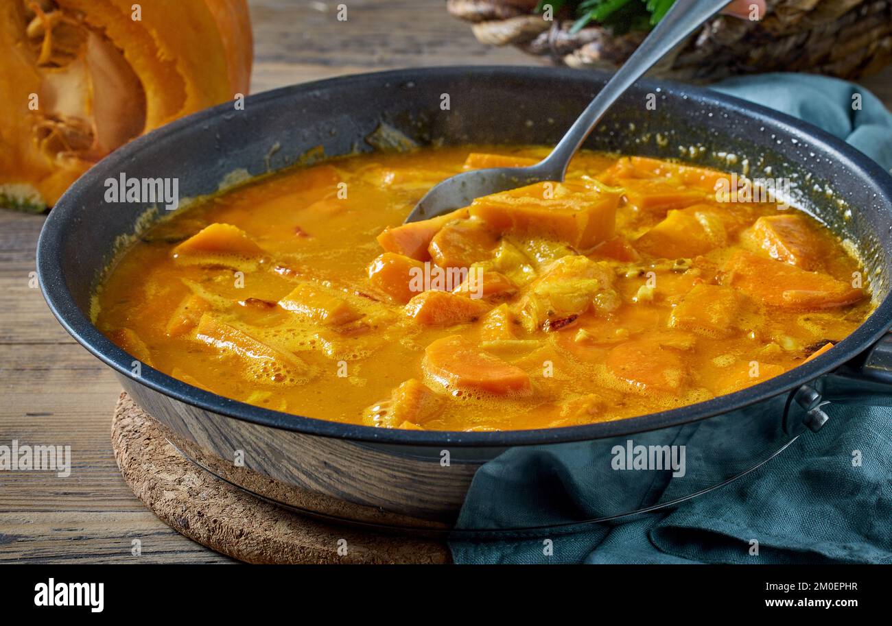 pumpkin and carrot stew in a cooking pan on rustic kitchen table ...