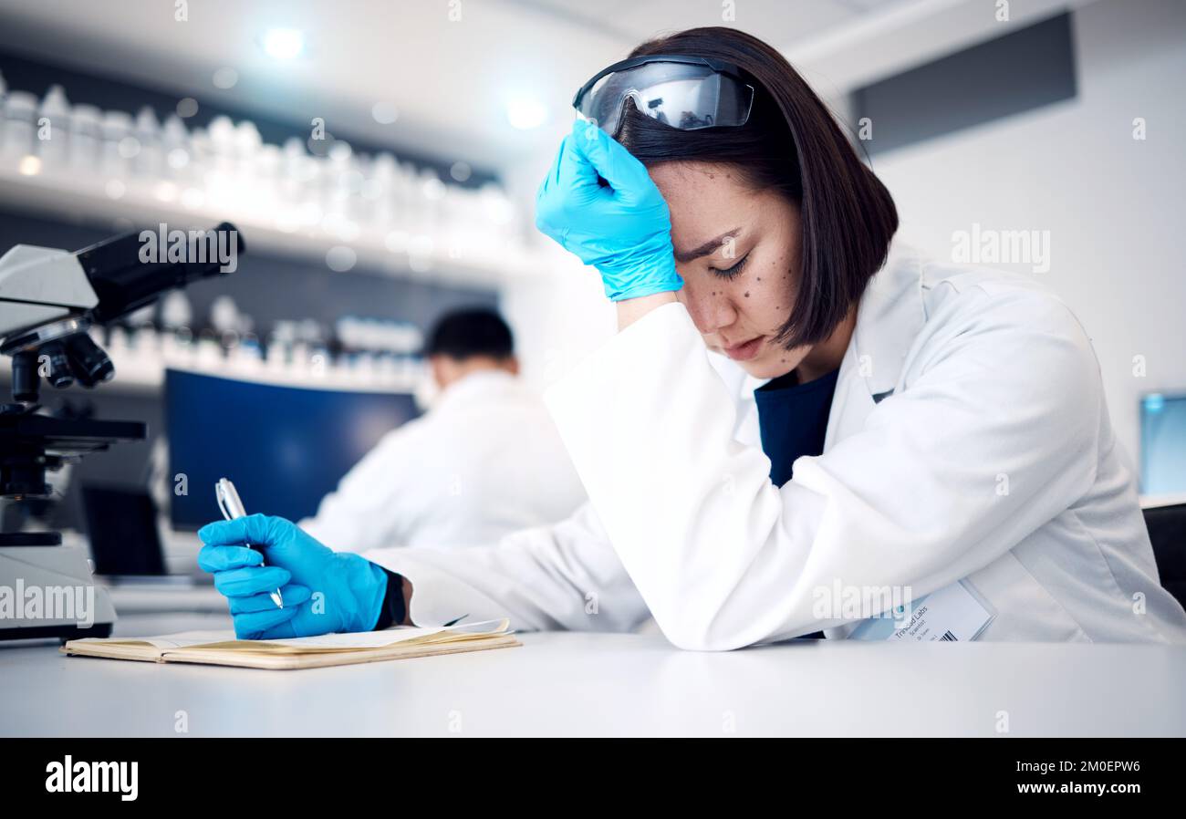 Scientist, headache stress and woman writing in notebook for research, planning report or ...
