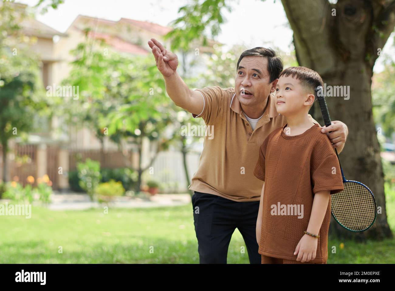 Grandfather explaining little boy how to play badminton Stock Photo - Alamy