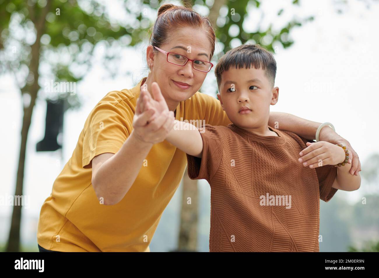 Grandmother teaching little boy exercising when they are spending ...