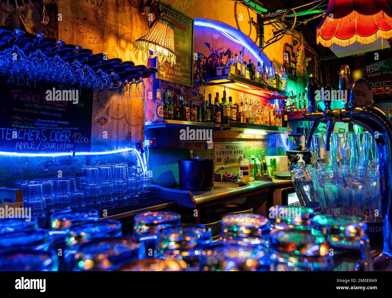 A closeup shot of bottles of spirits and liquor in a colorful bar with ...