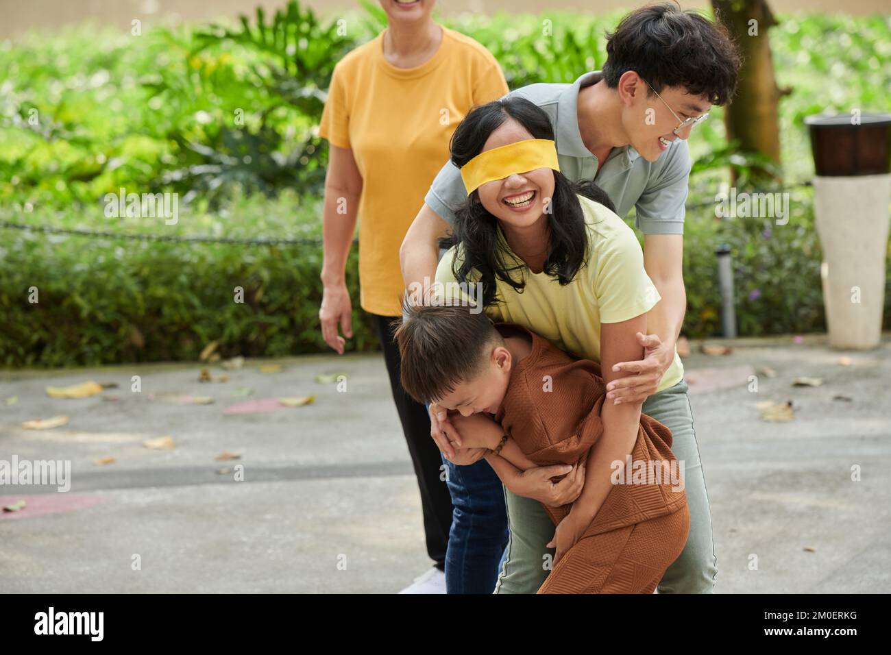 Happy family of three generation playing hide and seek in city park ...