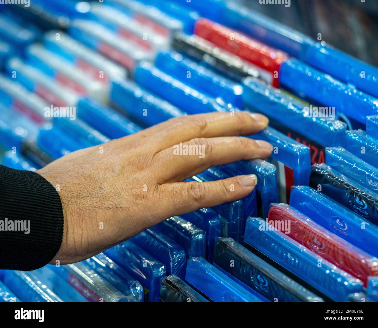 Hands searching and choosing movies and dvds on a shelf in a movie ...
