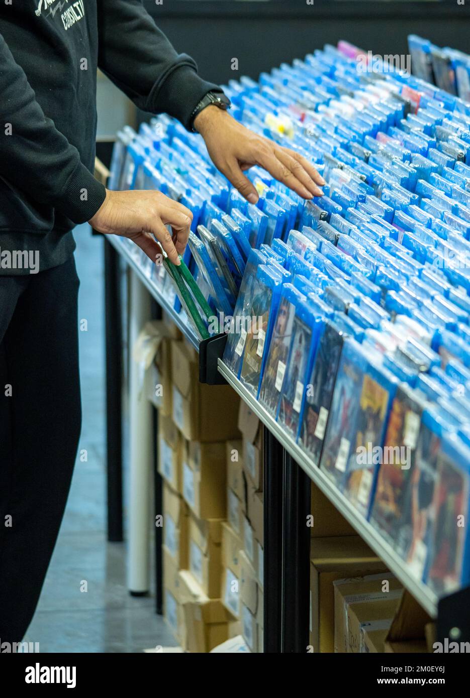 Hands searching and choosing movies and dvds on a shelf in a movie ...