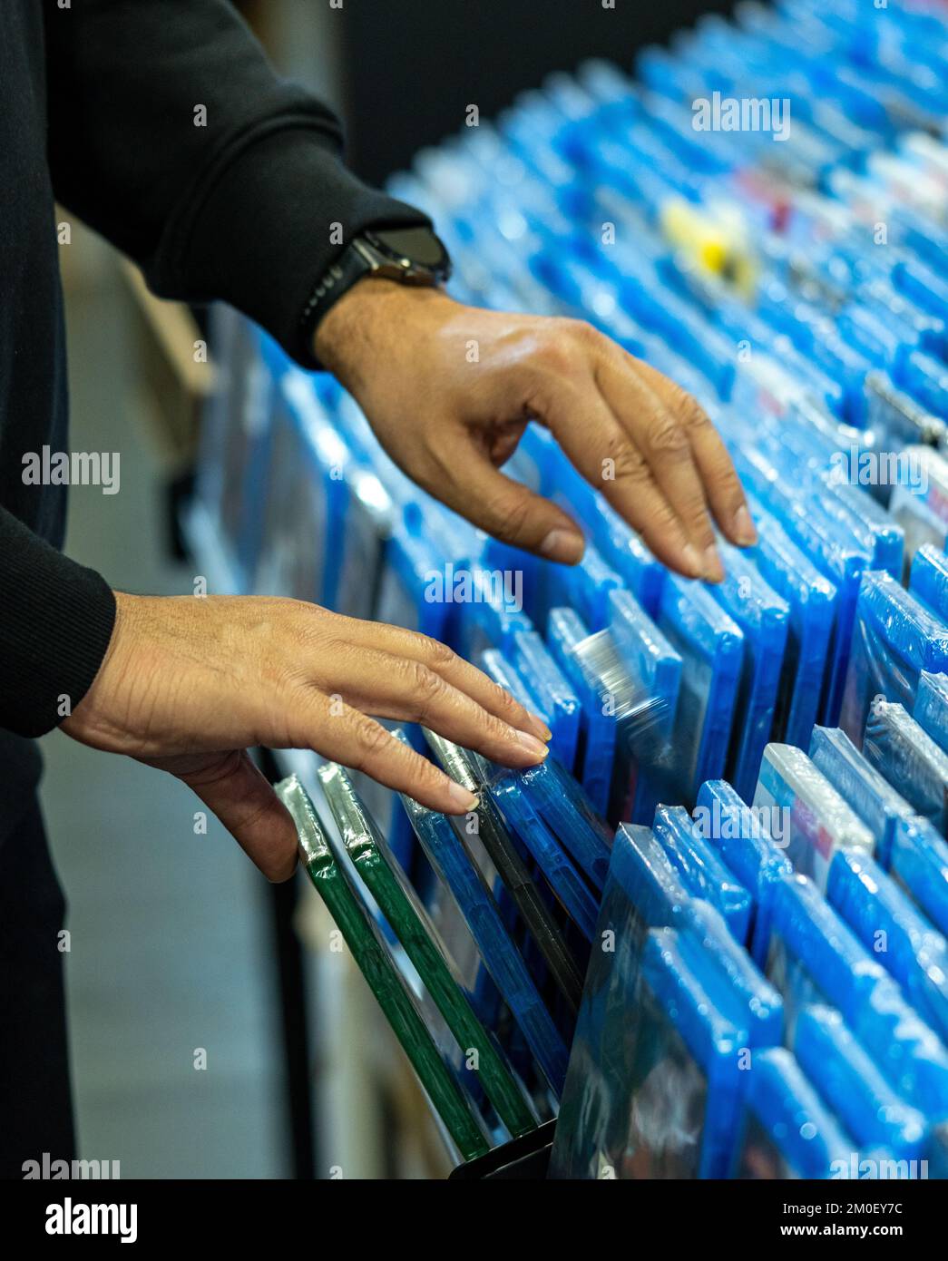 Hands searching and choosing movies and dvds on a shelf in a movie ...