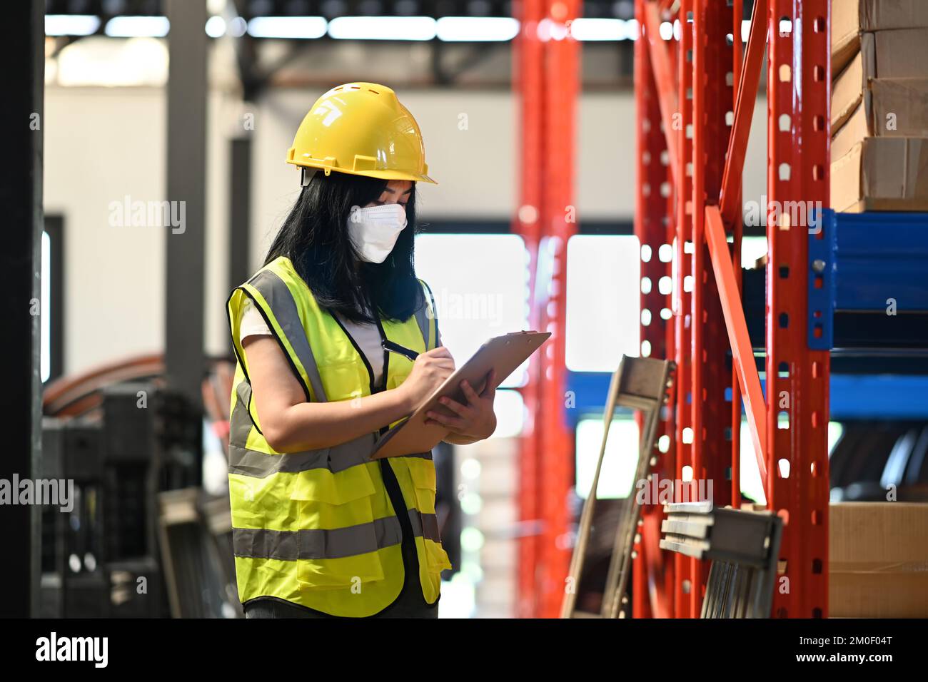 Asian woman warehouse workers using digital tablet while standing aisle ...
