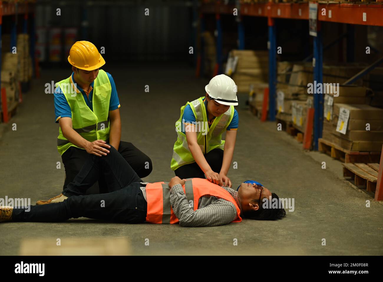 Male supervisor lying unconscious on the concrete floor and colleagues ...