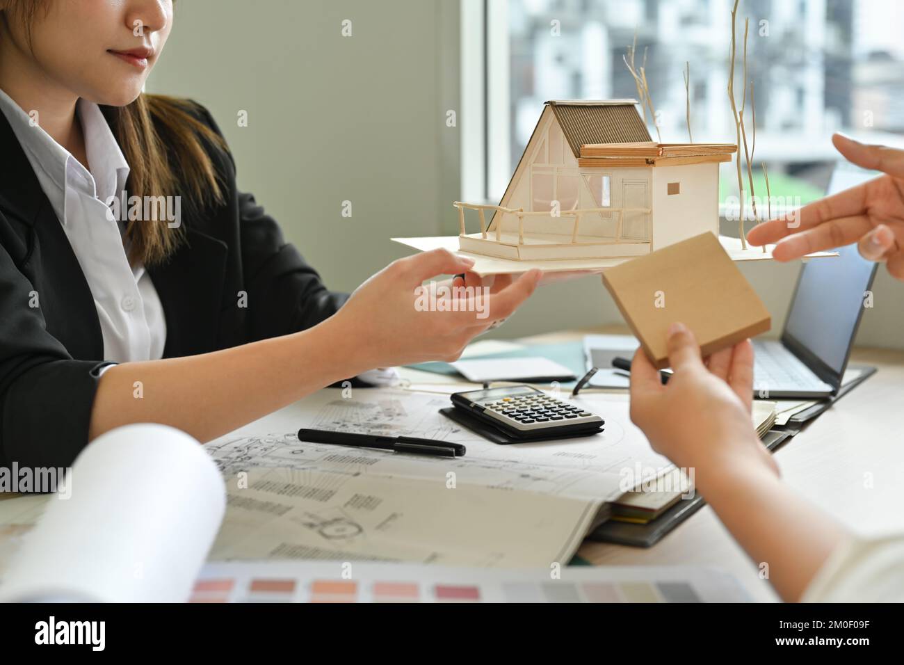 Architects team working on design of a construction plan and scale model house at co working ...