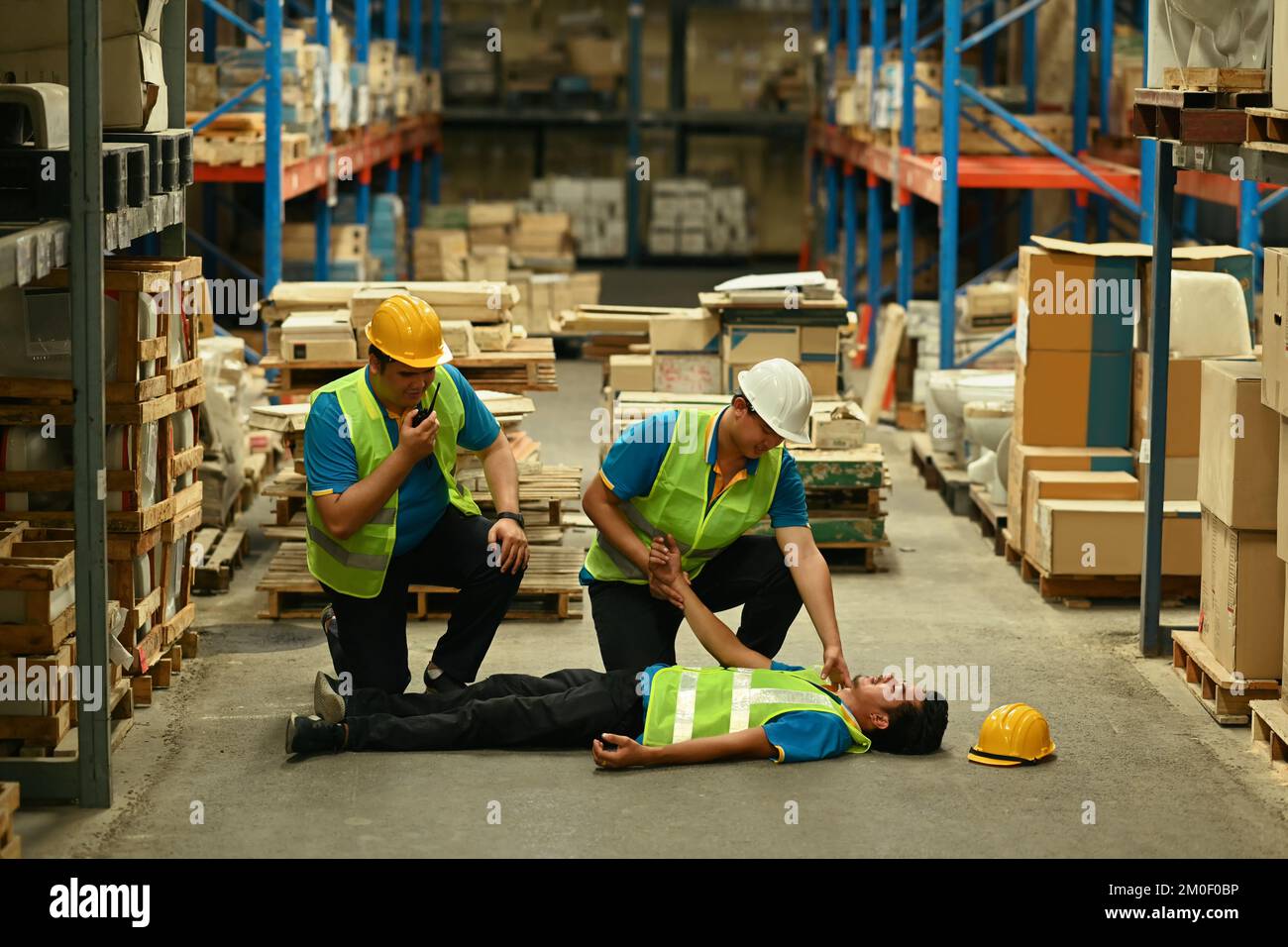 Two industrial worker are helping and giving the injured first aid to ...
