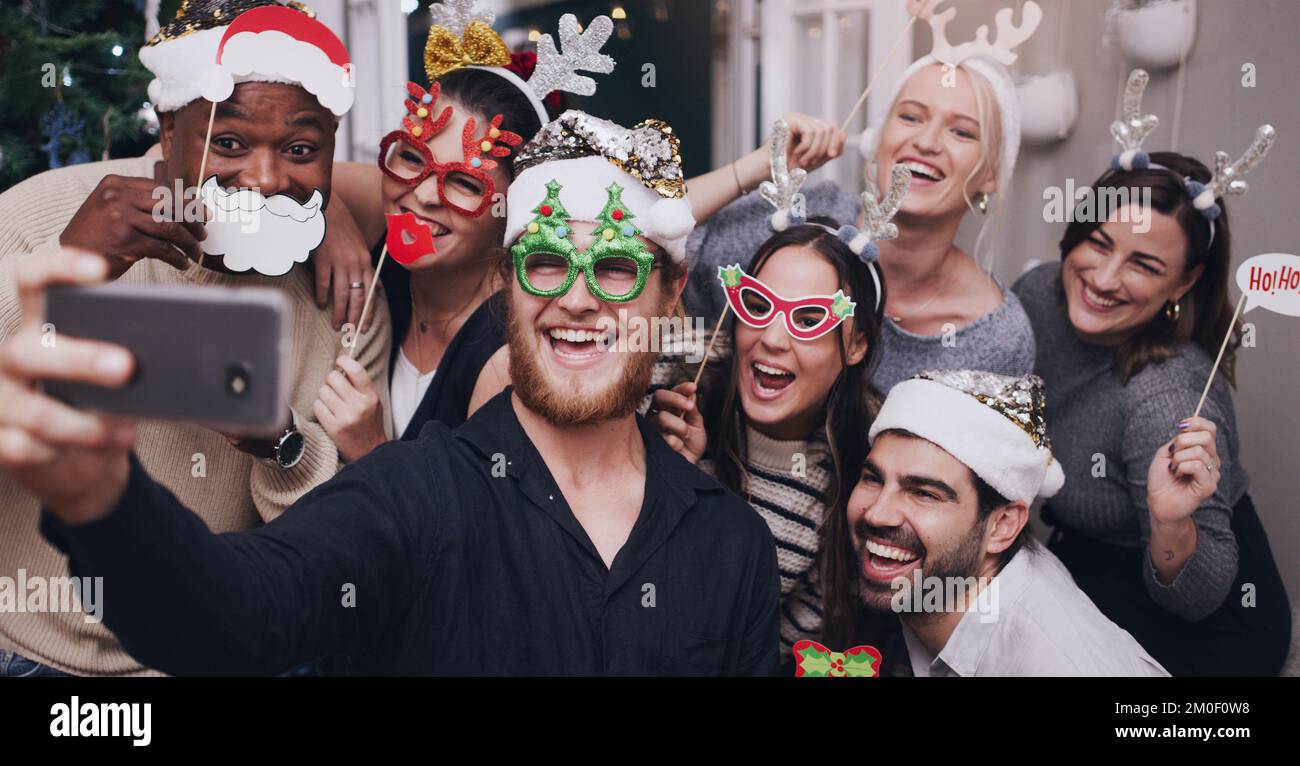 Christmas, party and friends taking a selfie on a phone together with ...