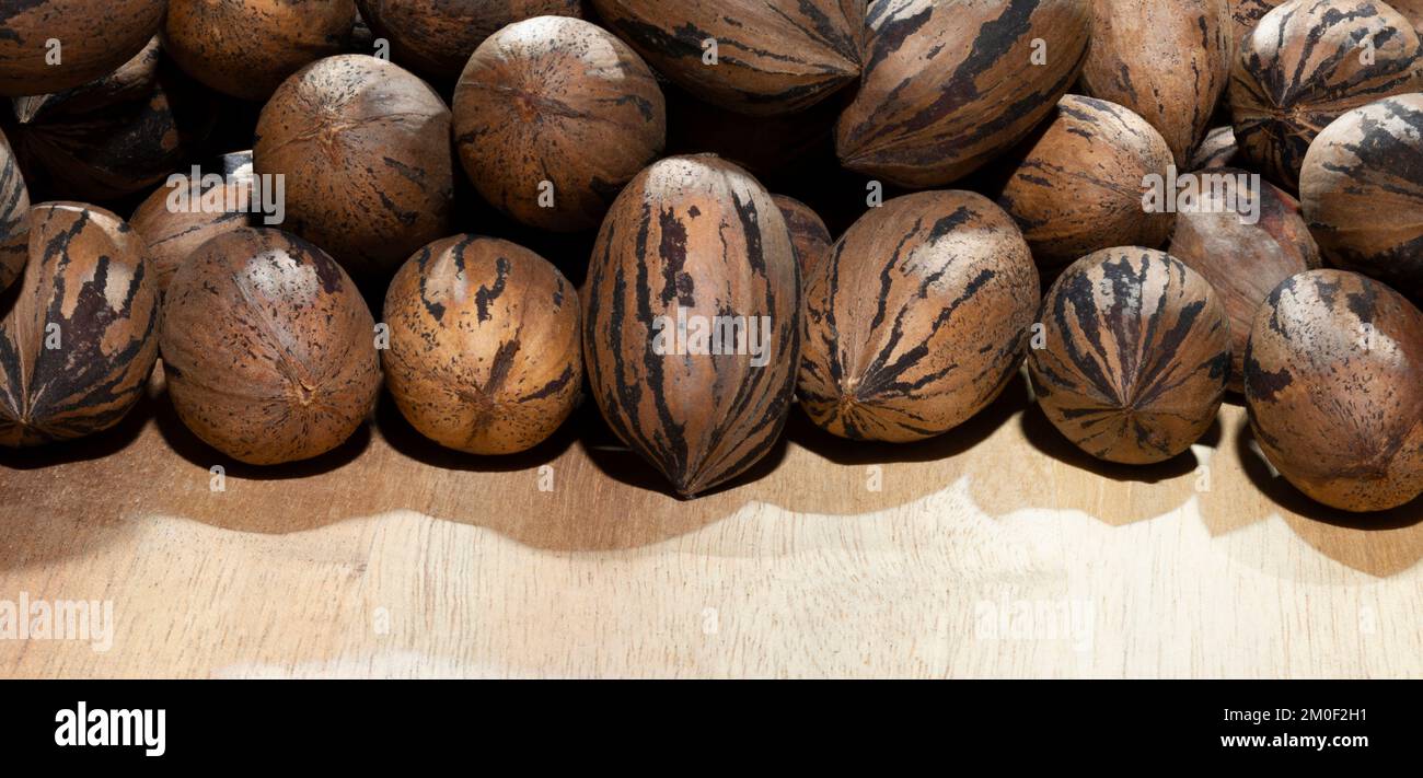 Pecans in the shell on a wood table ready to open Stock Photo - Alamy