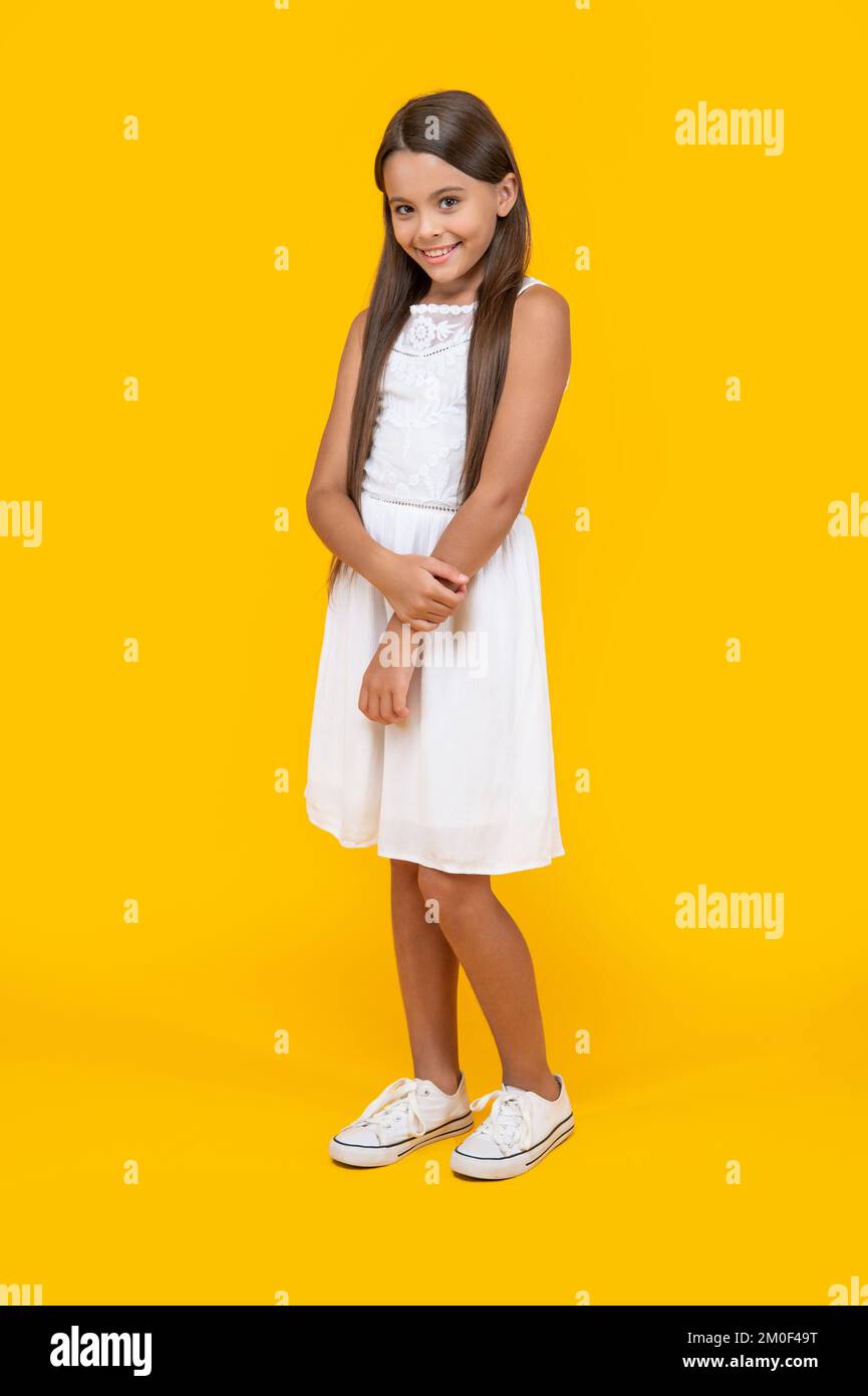 shy teen girl in white dress standing on yellow background Stock Photo ...
