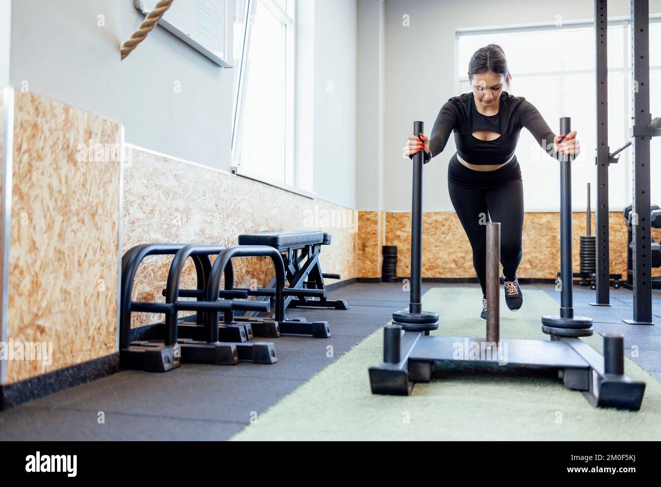 Fit young woman has training at a crossfit style on dark gray ...