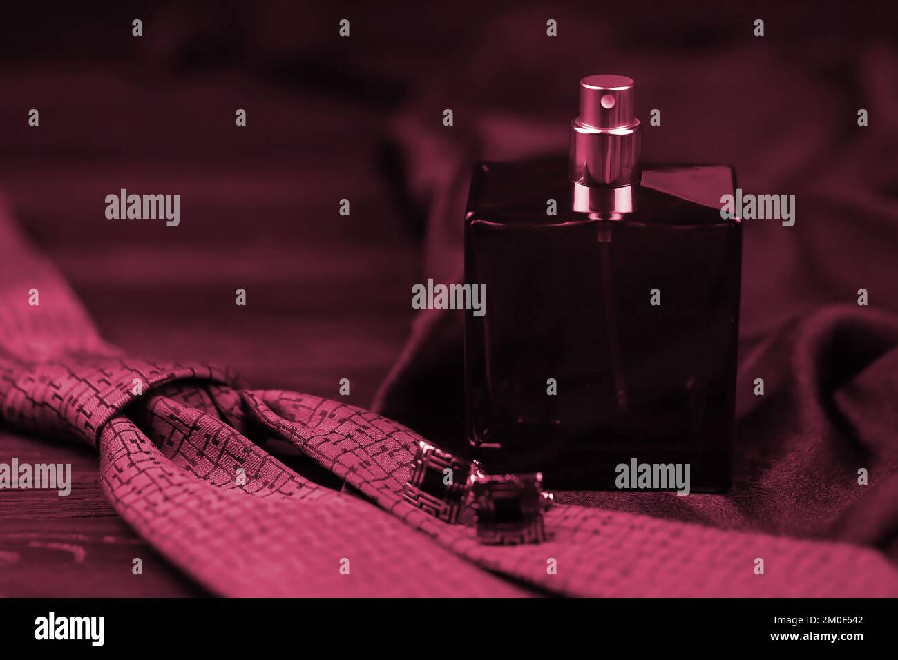 A bottle of mens cologne and cufflinks with blue tie lie on a black ...