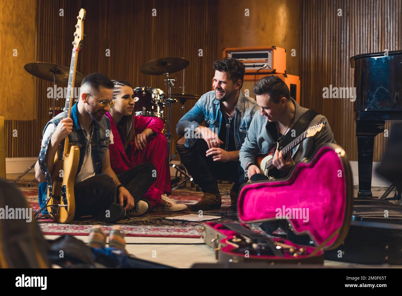 Music band members sitting on the floor in a rehearsal studio. High ...