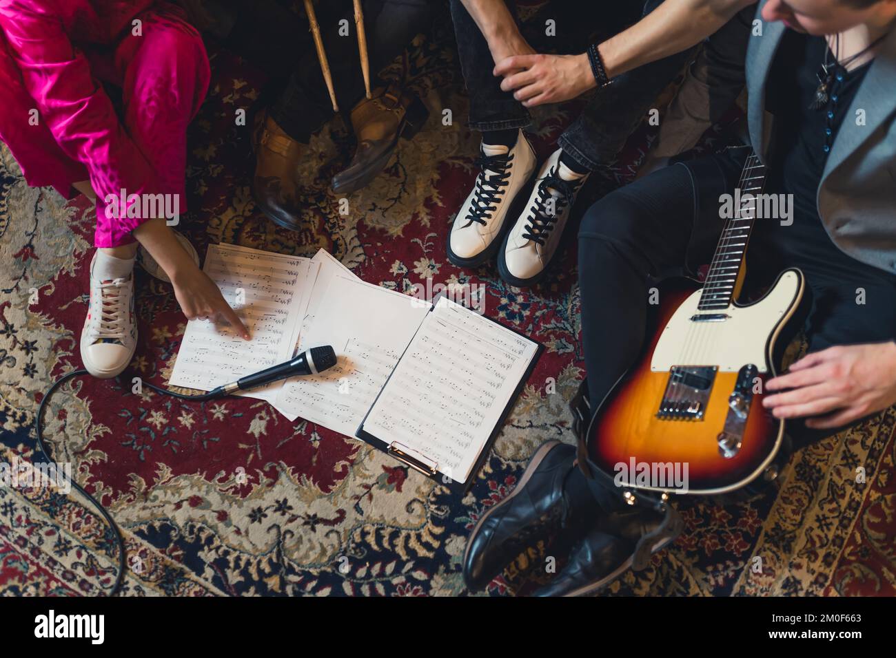 Music band learning a new song, sitting on the floor with notes. No ...