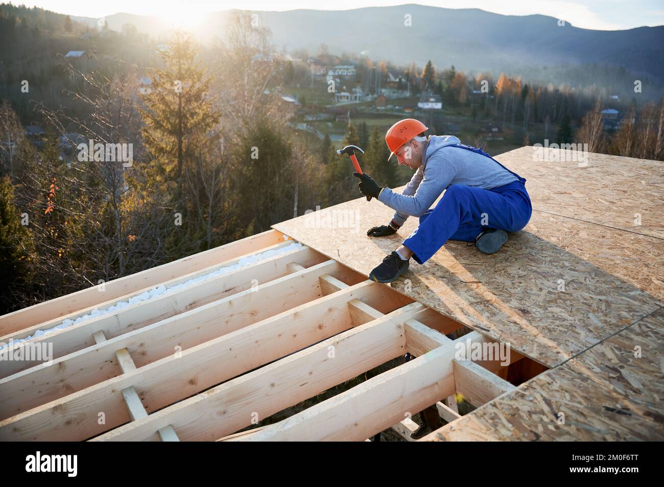 Carpenter hammering nail into OSB panel on the roof top of future ...