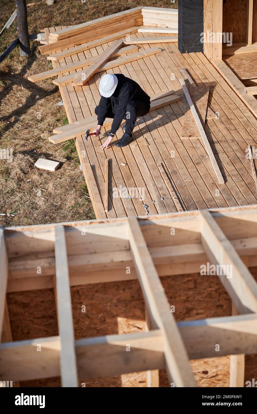 Man worker building wooden frame house. Carpenter hammering nail into ...