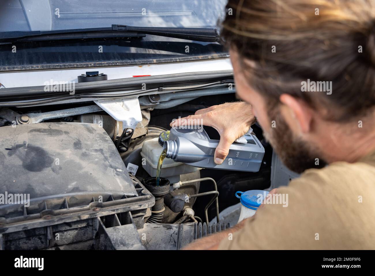 Man refilling oil into the engine of a van Stock Photo - Alamy