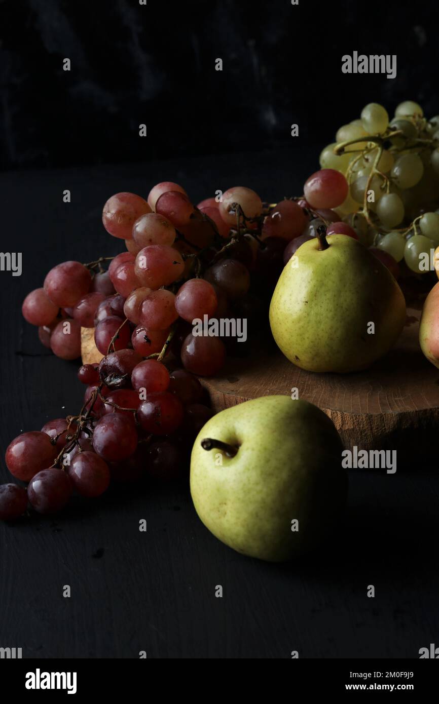 grape and pear fruits on a black background Stock Photo - Alamy