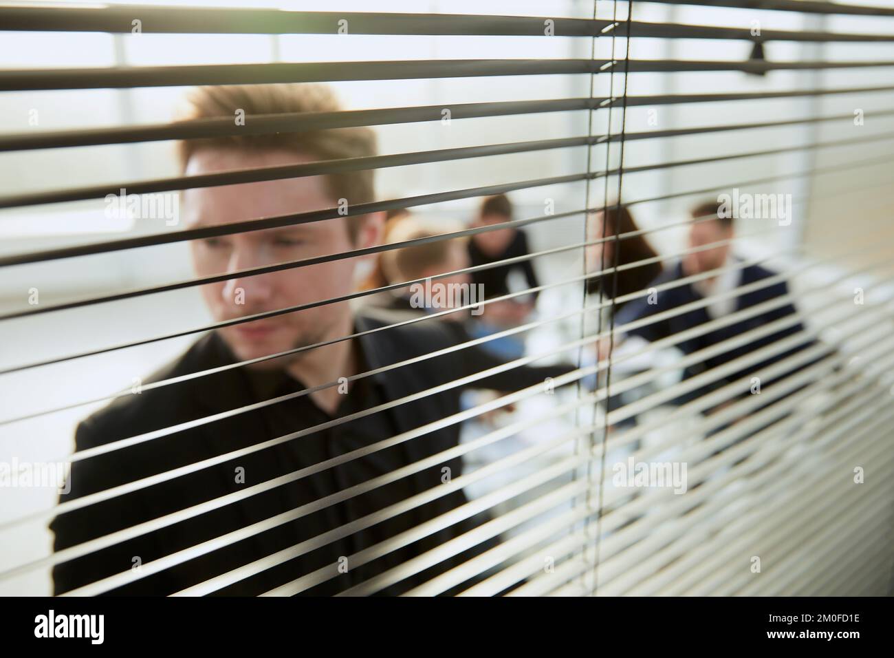 close up. smiling employee looking through office blinds Stock Photo ...