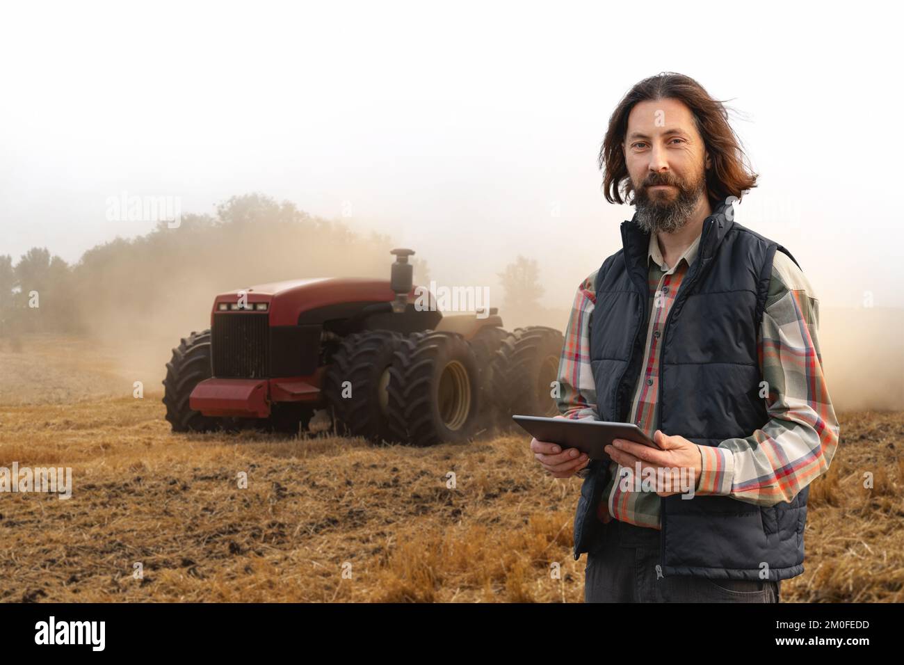 Farmer with digital tablet controls an autonomous tractor on a smart ...