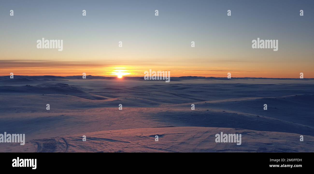 A panoramic view of the snow-covered landscape before an orange-shaded ...