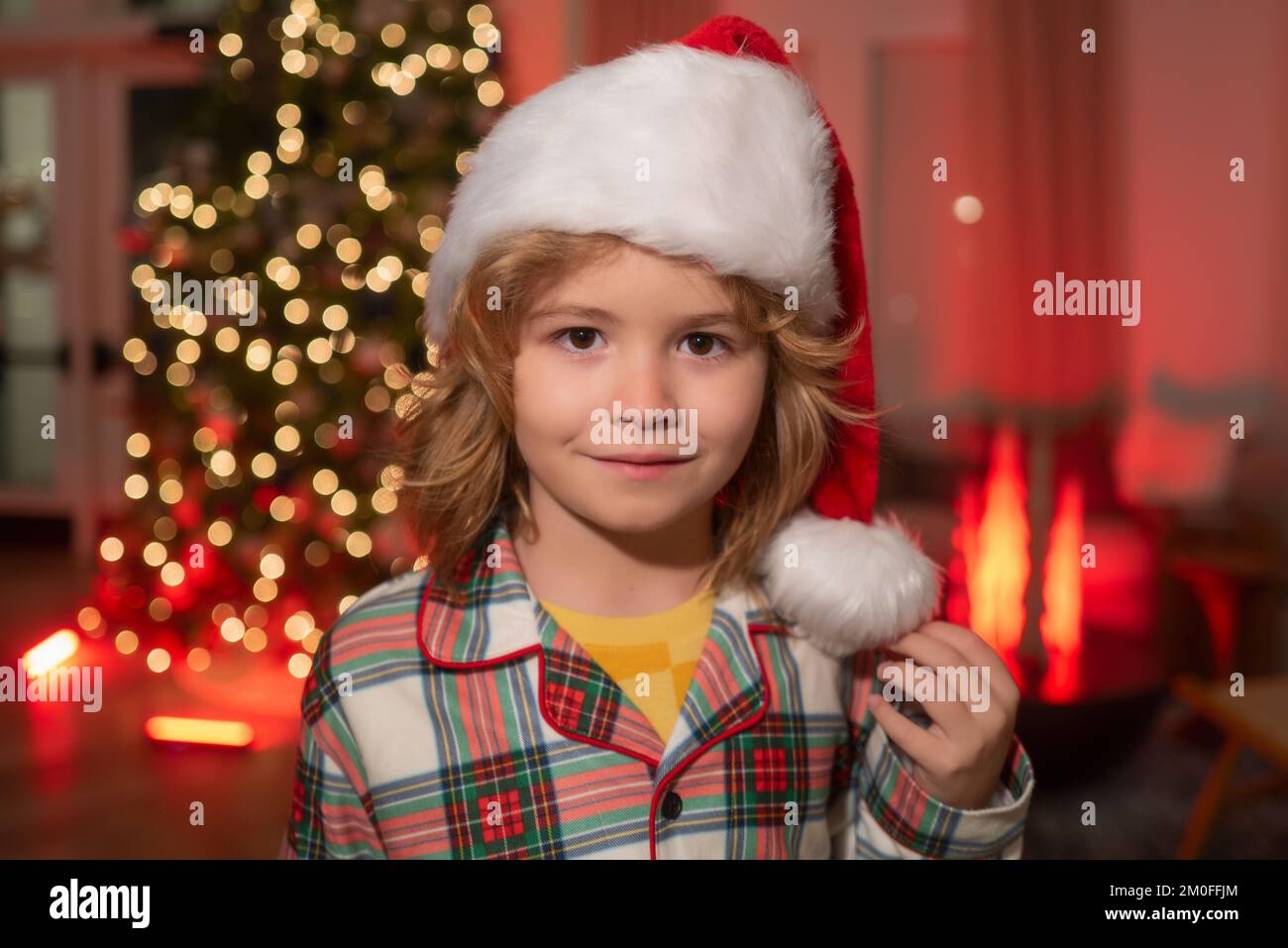 Kid in santa hat on front of night Christmas tree home background on ...