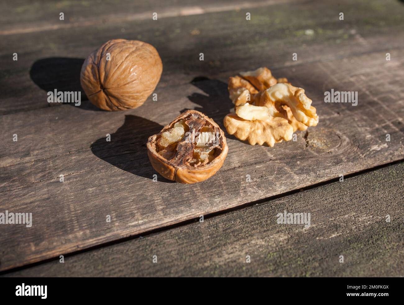 Walnuts over wooden picnic table. Natural light shot Stock Photo - Alamy