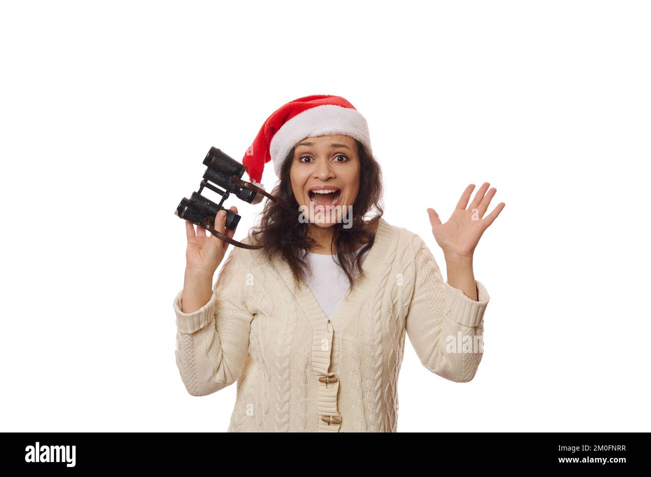 Stupefied woman in Santa hat with binoculars, looks forward at upcoming ...