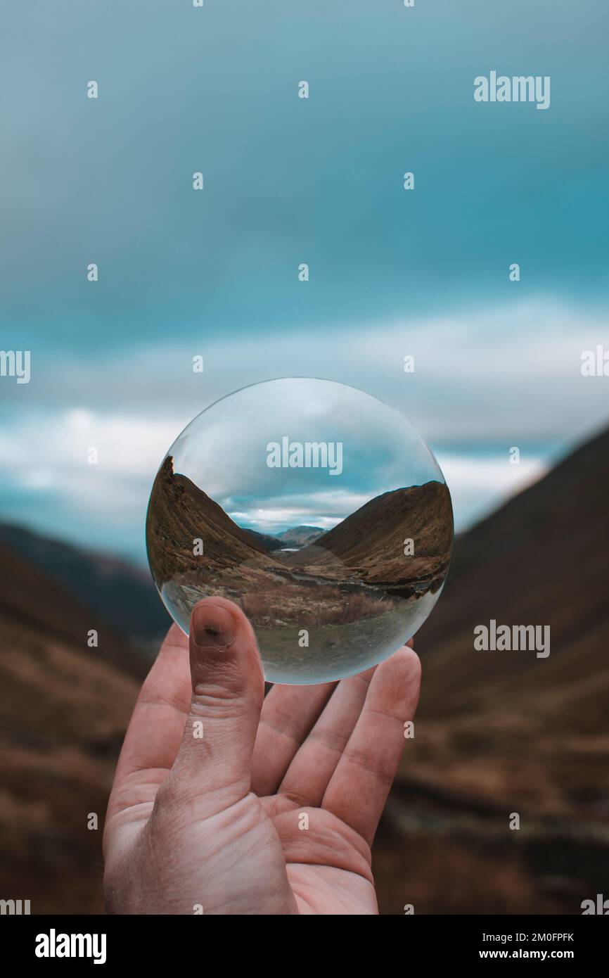 A vertical shot of a hand holding a crystal ball reflecting Kirkston ...