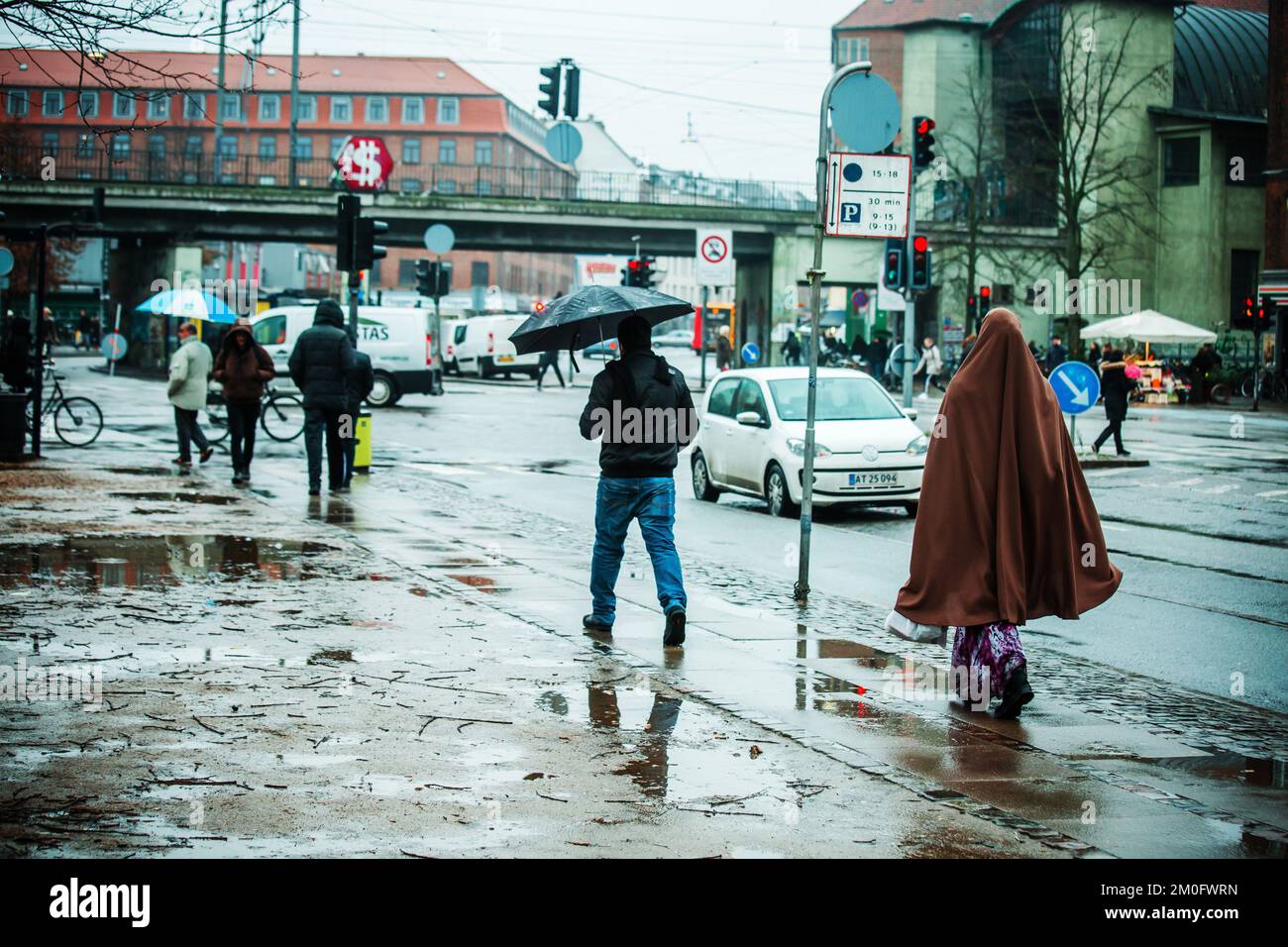 People on the street at Norrebro Station in the rain. Woman in burka ...