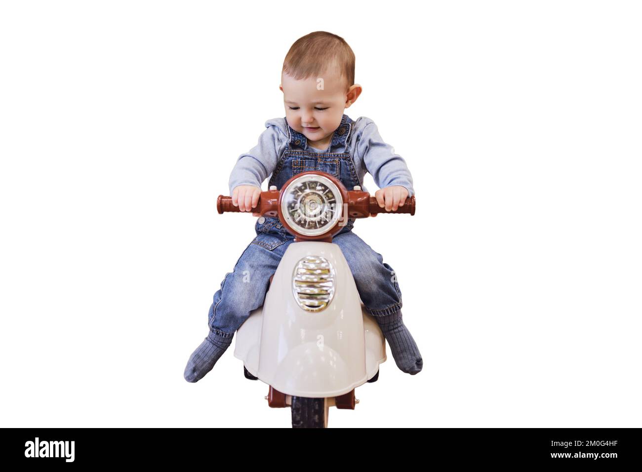 Happy baby boy rides a plastic children motorcycle in the playroom ...