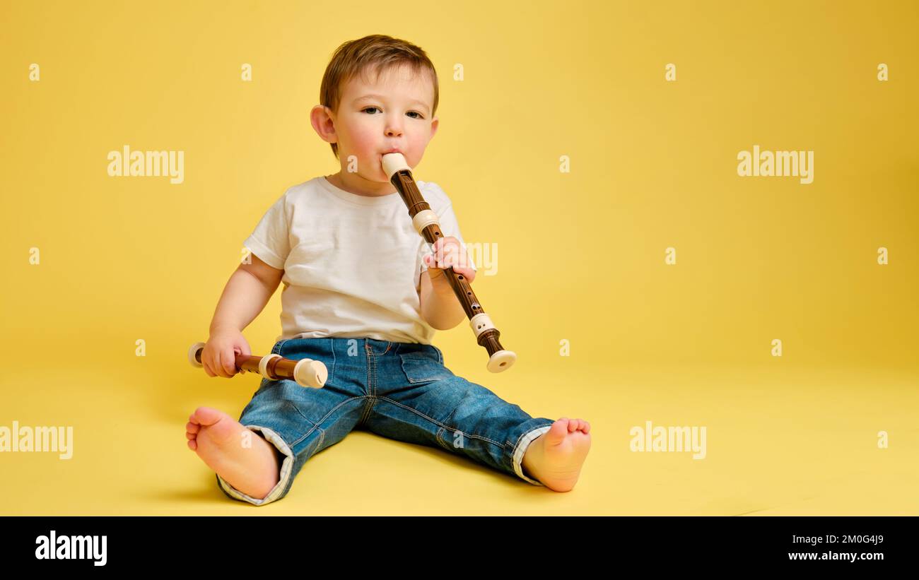 Toddler baby plays the flute, a child with a wind musical instrument on ...