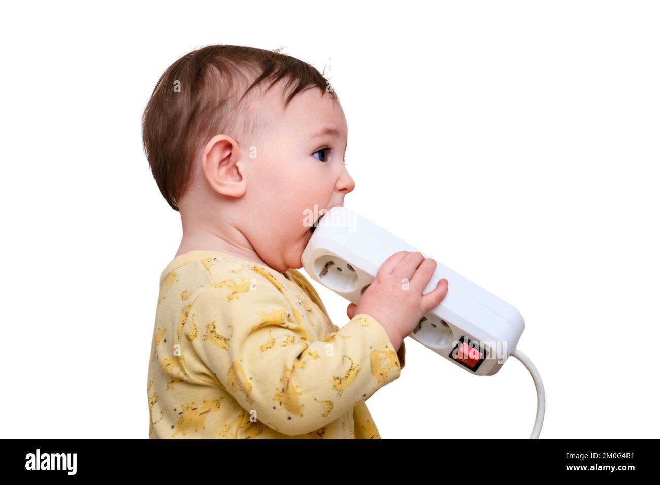 Toddler baby boy gnaws electrical wires while sitting on the floor ...