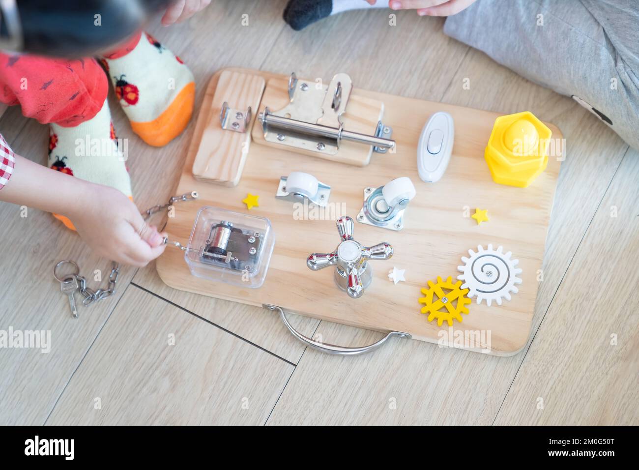 Two Children are playing with busy board toy on the wooden floor ...