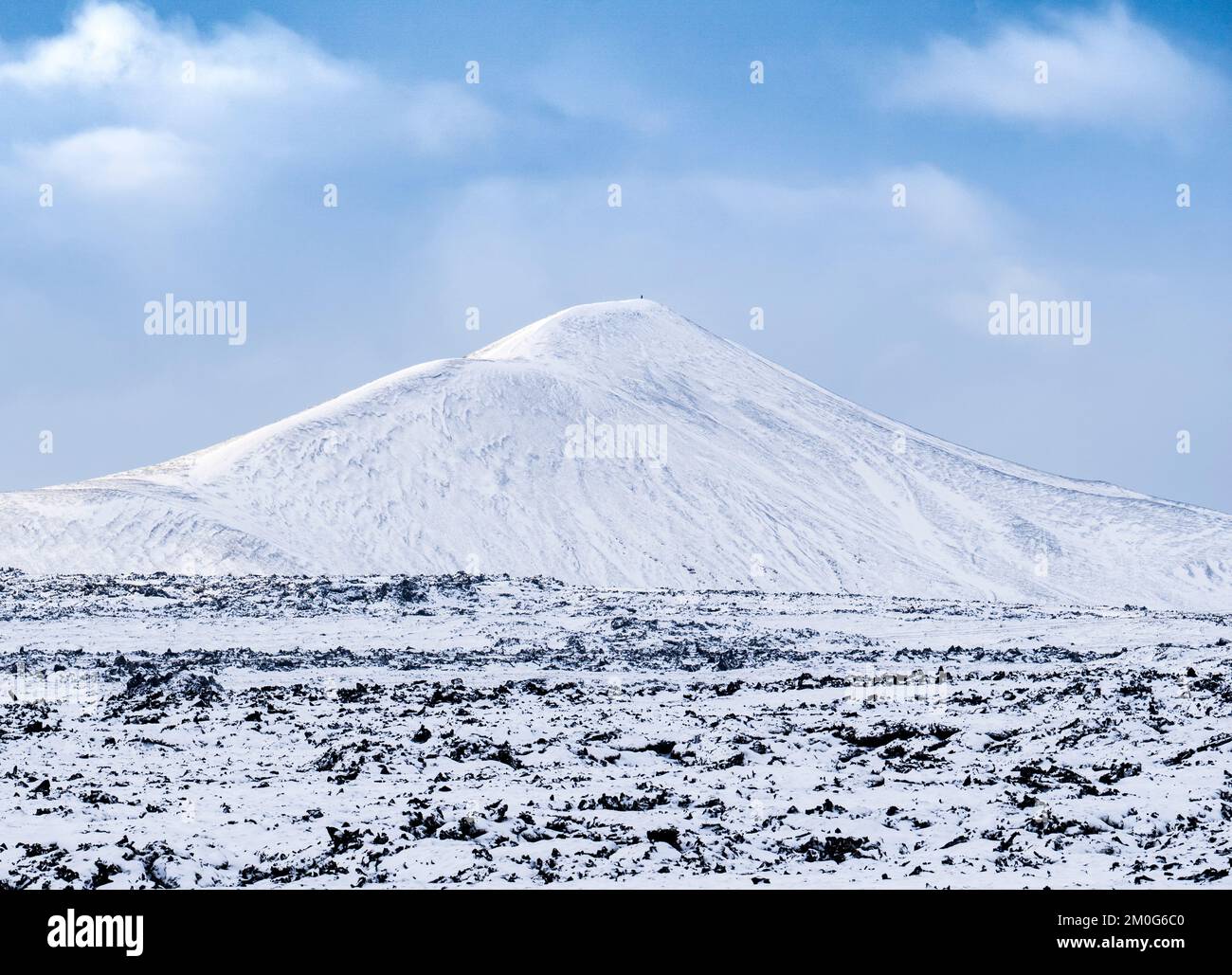 A wide lava field with a white snowy mountain in the background in ...